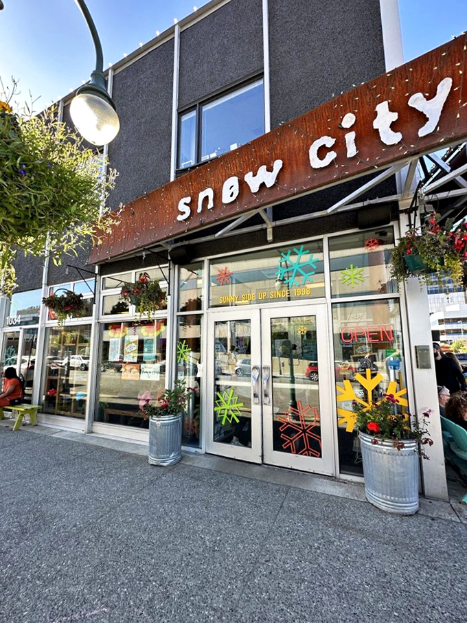 Welcome to Snow City Cafe, where the exterior is as inviting as a warm hug on a frosty Alaskan morning. Colorful flowers defy the chill, promising a cozy retreat inside.