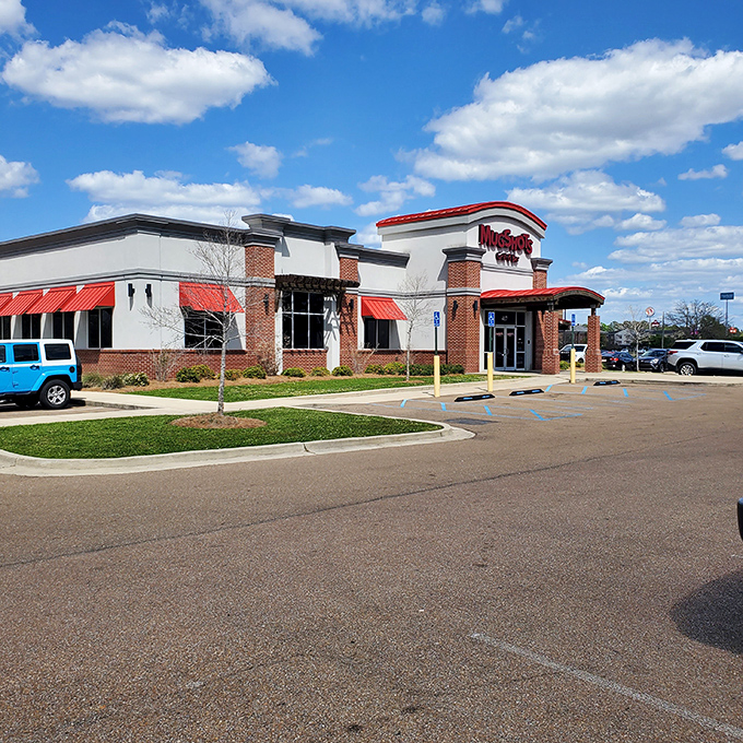 Welcome to flavor town! Mugshots Grill & Bar stands proud, its red awnings beckoning like a culinary lighthouse guiding hungry souls to delicious shores.
