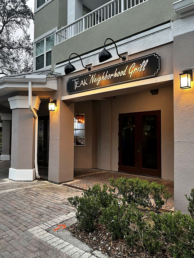 Welcome to burger paradise! Teak Neighborhood Grill's inviting facade promises a feast for the senses, with warm lighting and rustic charm that'll make you feel right at home.