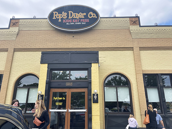 The sunshine-yellow exterior of Pop's Diner Co. stands out like a beacon for breakfast lovers, promising comfort food salvation with its cheerful "Kids Eat Free" sign.