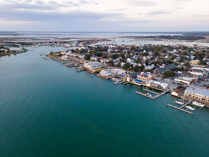Sunset casts golden light over Beaufort's harbor, where sailboats rest after a day at sea and historic homes stand watch along tree-lined streets.