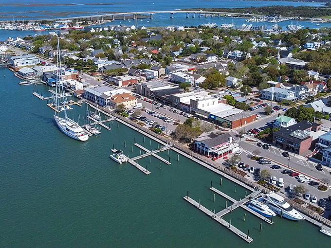 Sunset casts golden light over Beaufort's harbor, where sailboats rest after a day at sea and historic homes stand watch along tree-lined streets.