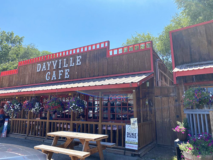 The wooden facade of Dayville Cafe stands proudly against the Oregon sky, hanging flower baskets adding splashes of color like nature's welcome committee.