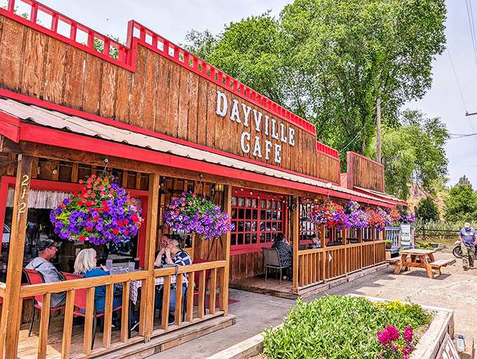 The wooden facade of Dayville Cafe stands proudly against the Oregon sky, hanging flower baskets adding splashes of color like nature's welcome committee.