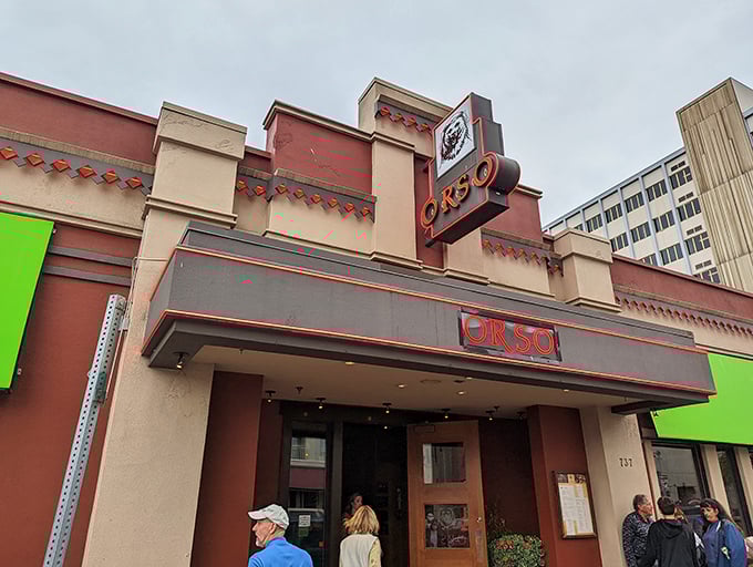 Orso's exterior beckons like a warm hug on a chilly Alaskan night. Red brick, green awnings, and twinkling lights promise a cozy culinary adventure inside.