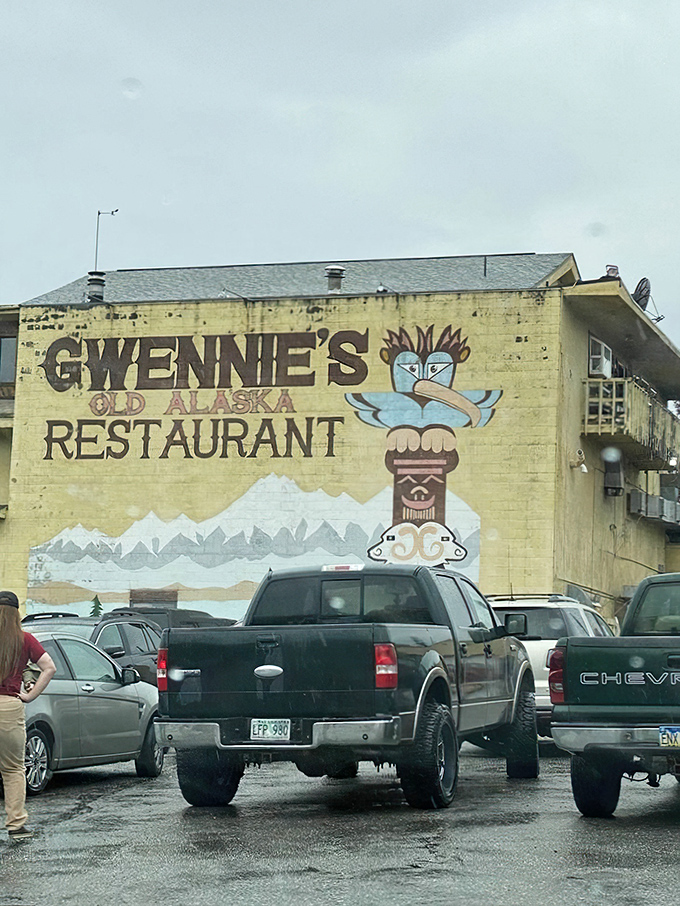 The pale yellow exterior of Gwennie's stands like a cheerful sentinel against Alaska's often-gray skies, complete with iconic totem pole mural.
