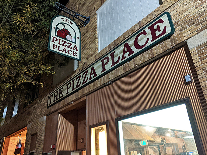 Welcome to pizza paradise! The Pizza Place's charming exterior beckons like a siren song to hungry travelers, promising cheesy delights within its brick walls.