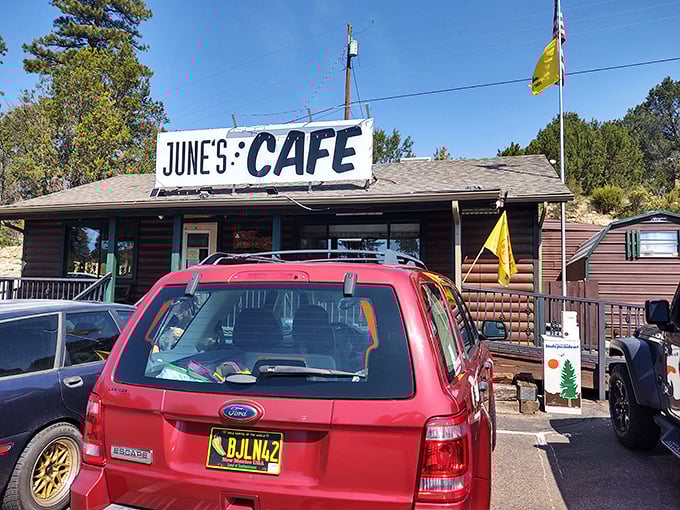 The log cabin charm of June's Cafe stands proudly against Arizona's blue sky, complete with American flag – a beacon of breakfast hope for hungry travelers.