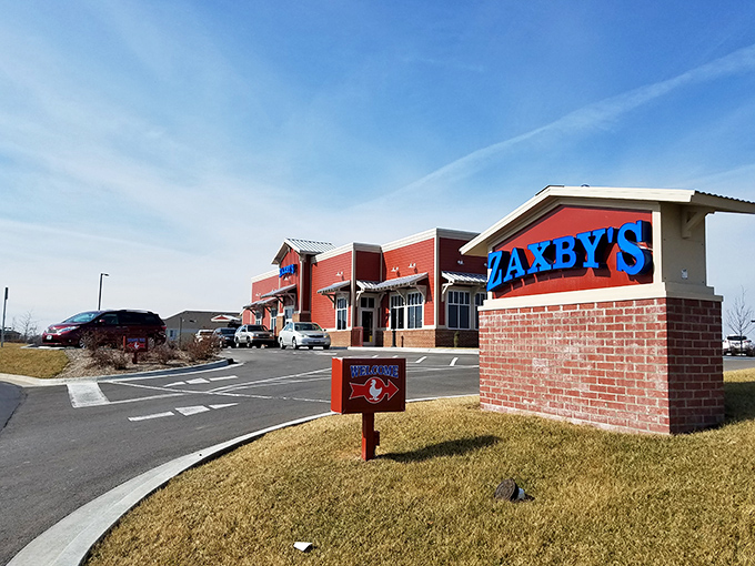 Welcome to flavor town! Zaxby's bold blue sign beckons like a neon lighthouse, guiding hungry souls to a chicken paradise.