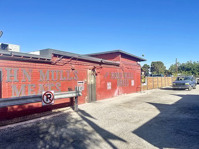 The unassuming red exterior of Road Kill Grill stands like a barbecue beacon in the desert, promising smoky treasures within its humble walls. 