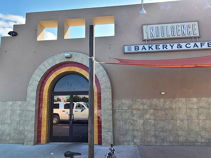 Welcome to flavor town! Indulgence Bakery & Cafe's exterior promises a rainbow of tastes, with its vibrant arch beckoning food lovers like a culinary pot of gold.