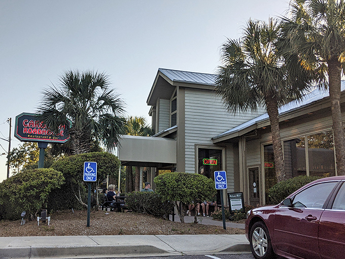 Palm trees stand sentinel alongside the unassuming exterior of Carolina Roadhouse, where culinary treasures await behind that modest "EXIT ONLY" sign.