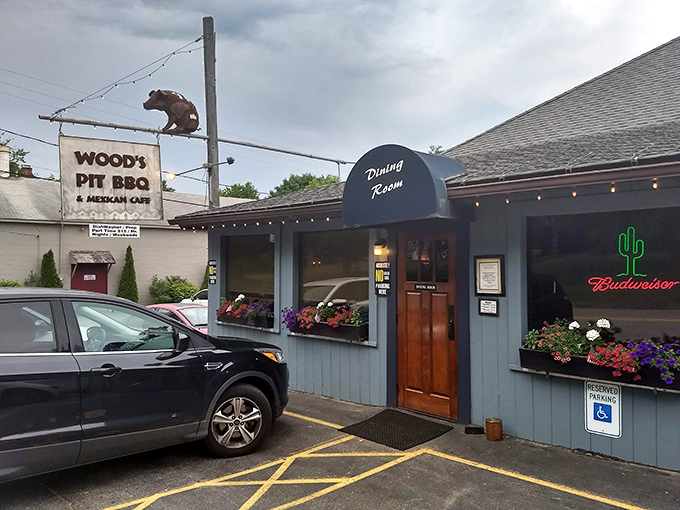 Welcome to BBQ paradise! Wood's Pit BBQ & Mexican Cafe's exterior promises a flavor fiesta, with its charming blue-gray facade and inviting neon cactus sign.