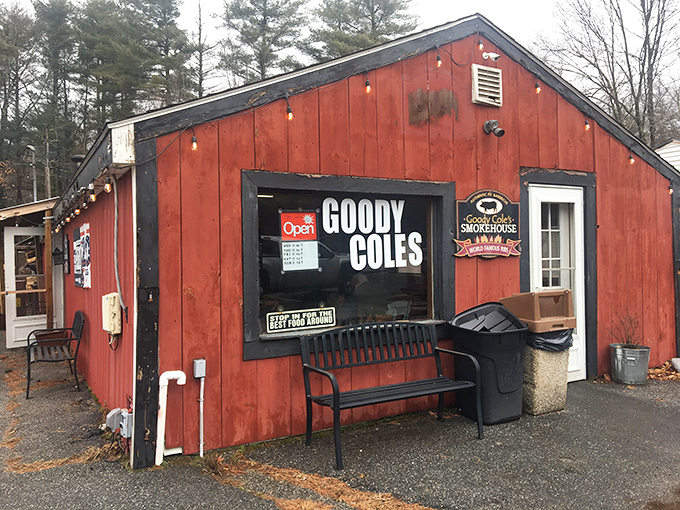 A barn-red beacon of barbecue bliss! Goody Cole's Smokehouse stands proud, with stacks of wood hinting at the smoky delights within.