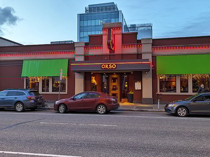 Orso's exterior beckons like a warm hug on a chilly Alaskan night. Red brick, green awnings, and twinkling lights promise a cozy culinary adventure inside.