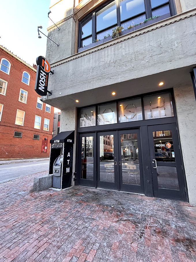 Welcome to burger paradise! Nosh's vibrant exterior promises a feast for the senses, with its eye-catching orange tables inviting you to sit and savor.