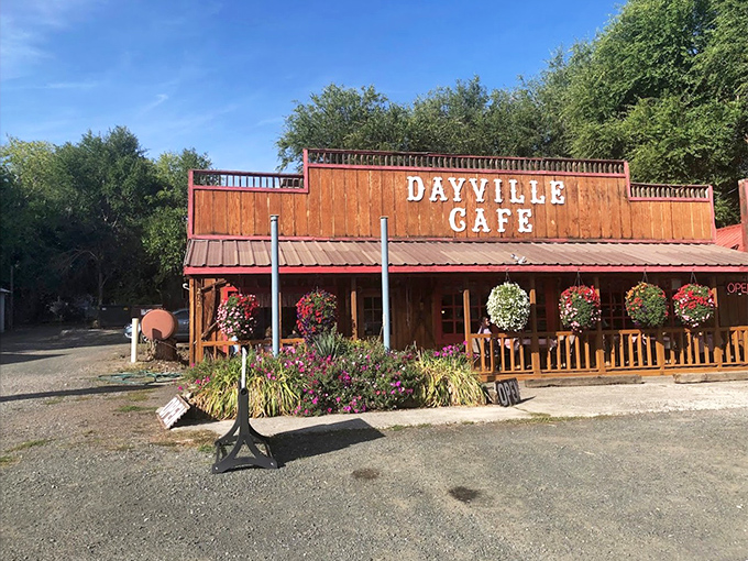 The wooden facade of Dayville Cafe stands proudly against the Oregon sky, hanging flower baskets adding splashes of color like nature's welcome committee.