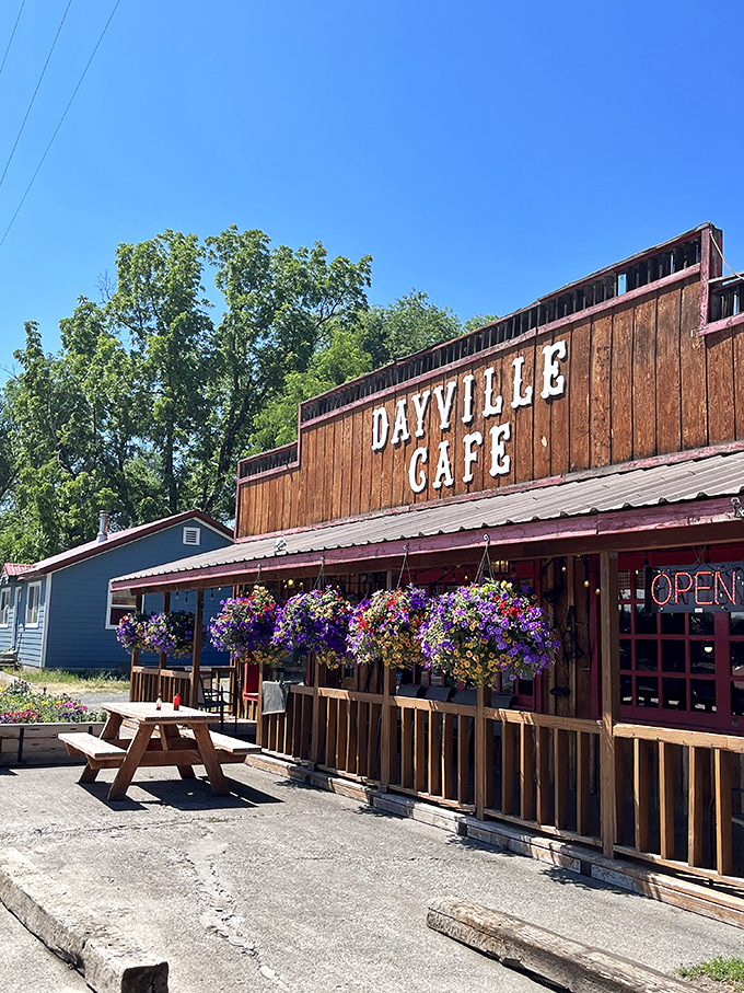 The wooden facade of Dayville Cafe stands proudly against the Oregon sky, hanging flower baskets adding splashes of color like nature's welcome committee.