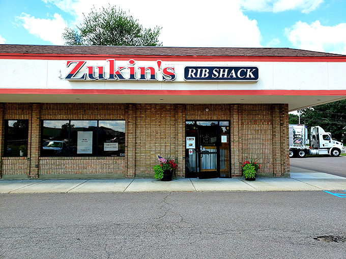 Welcome to BBQ paradise! Zukin's Rib Shack stands proud, its red and white sign a beacon of hope for hungry souls seeking smoky salvation.