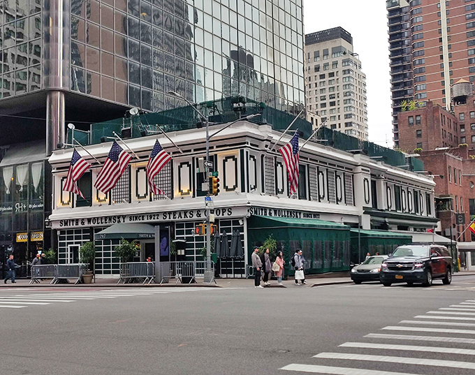 The iconic white building with green awnings stands like a time capsule amid Manhattan's glass towers, American flags proudly waving above this temple of beef.