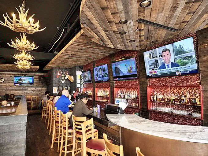 The bar area: where sports fans and food lovers unite. It's like your favorite pub got a cabin-chic makeover, complete with antler chandeliers.