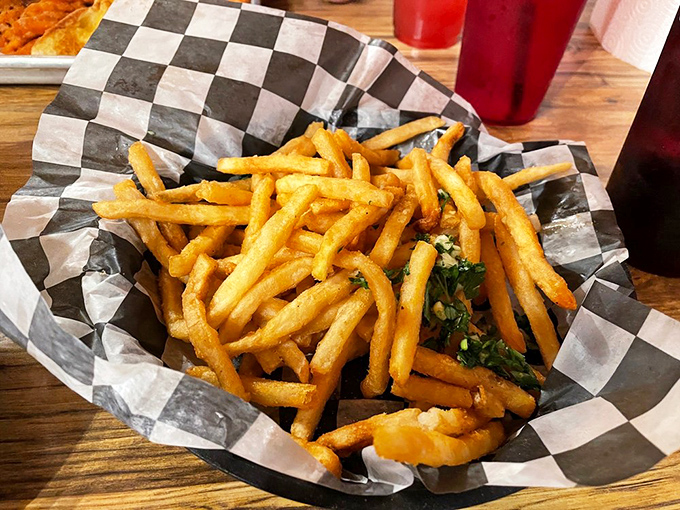 Fries that achieve the golden ratio of crispy exterior to fluffy interior, served in checkered paper like edible chess pieces.