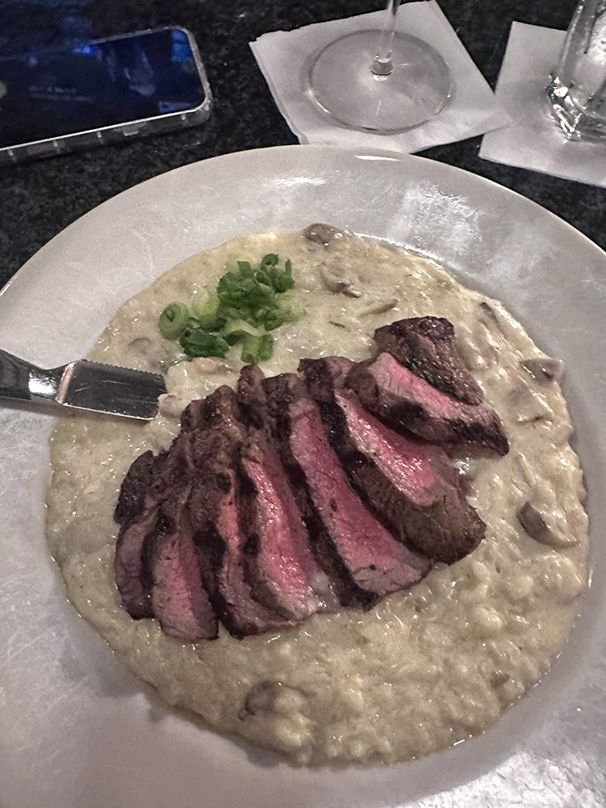 Steak sliced over creamy mushroom risotto&mdash;proof that surf 'n turf isn't the only perfect pairing. Those green onions aren't just garnish&mdash;they're the fresh high notes in this savory symphony.