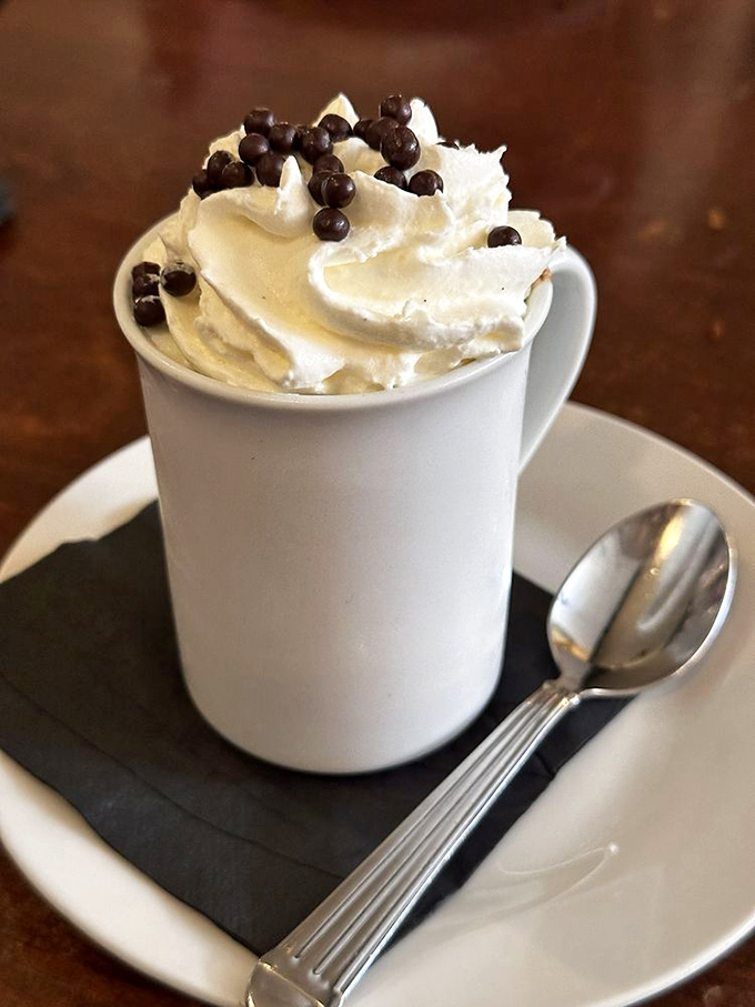 Hot chocolate that wears its whipped cream like a cloud-topped crown, with chocolate pearls adding just the right touch of fancy.