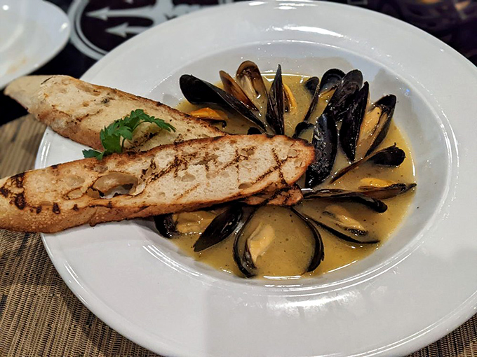 Mussels bathing in a golden broth, with crusty bread standing by for dipping duty. It's like a little ocean jacuzzi party on your plate.