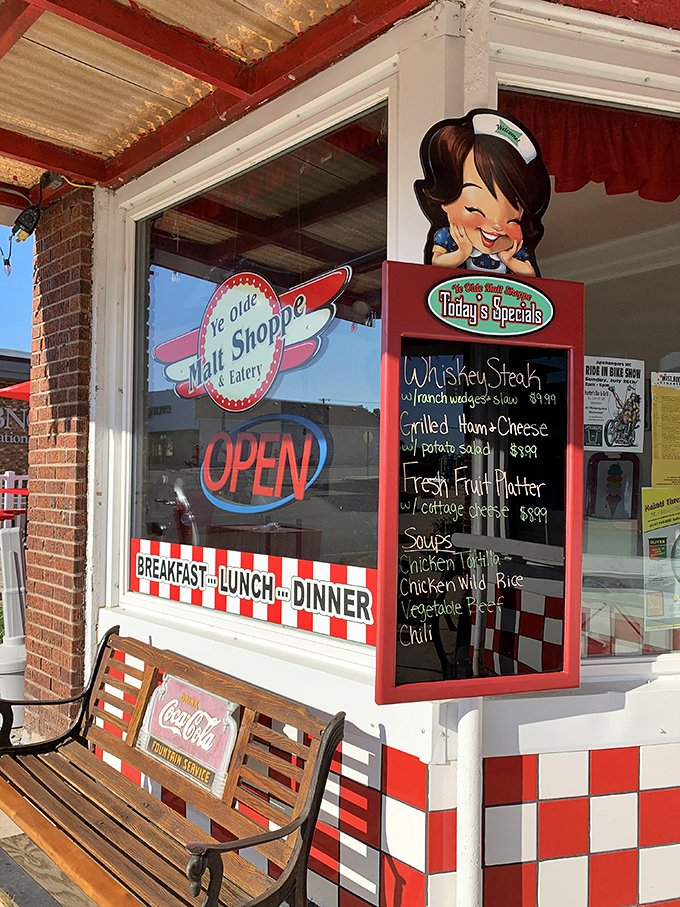The store window: where promises of deliciousness meet small-town charm. That cartoon waitress knows something we don't &ndash; probably where they hide the extra sprinkles.