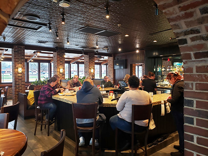 The bar area buzzes with conversation as patrons gather around, proving that good food brings people together better than any social media platform.