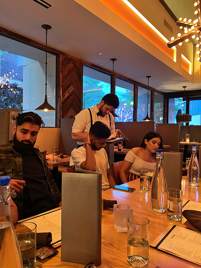 The warm, amber-lit dining room creates the perfect backdrop for conversations that flow as easily as the drinks being served.