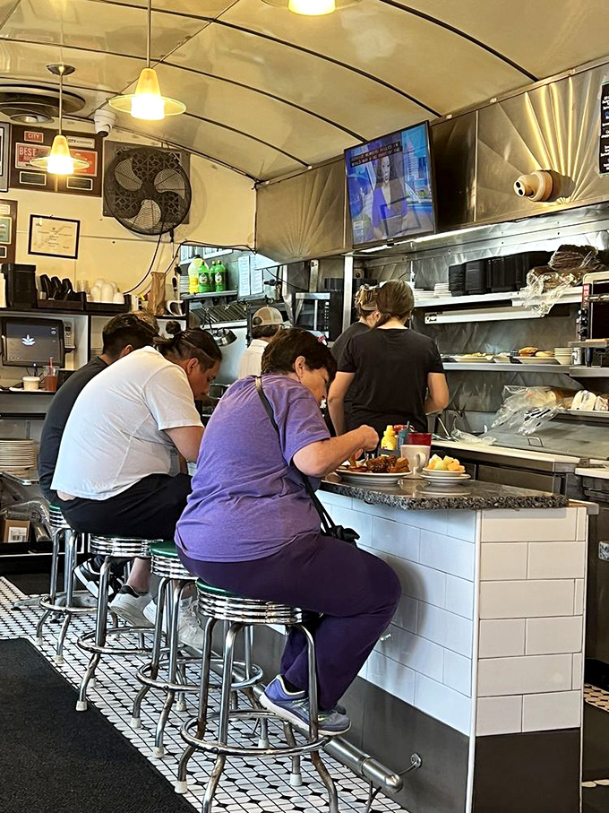 The counter seats&mdash;where regulars perch like birds on a wire, watching the kitchen ballet while trading neighborhood gossip.