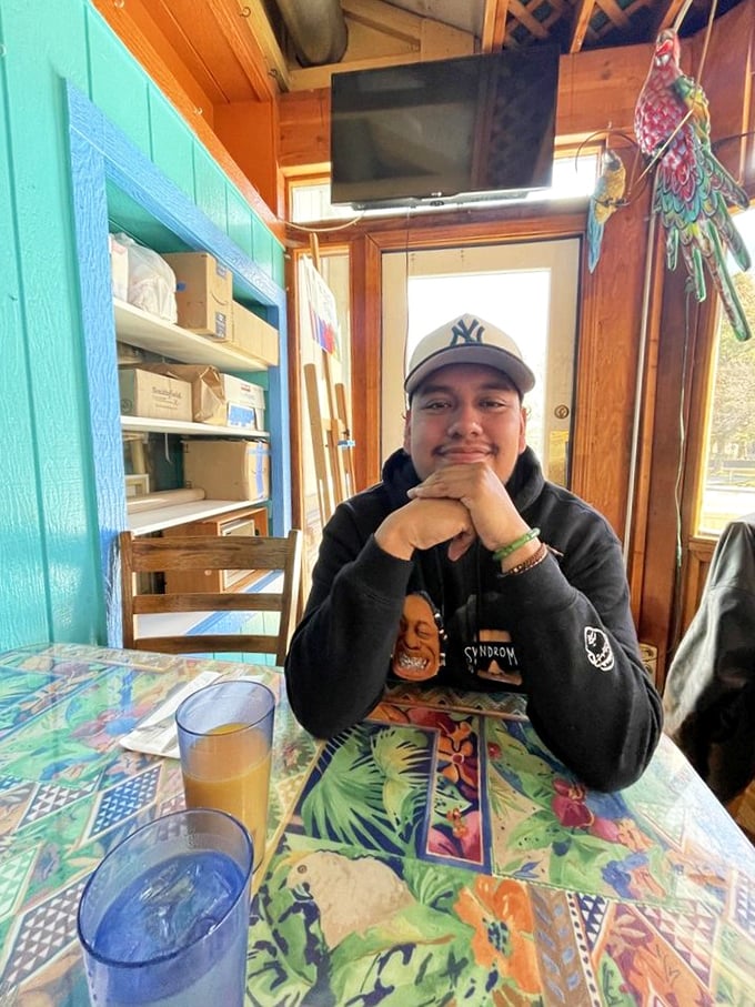 No need to identify the person in this image, but the colorful tablecloths and bright interior create a cheerful dining atmosphere.