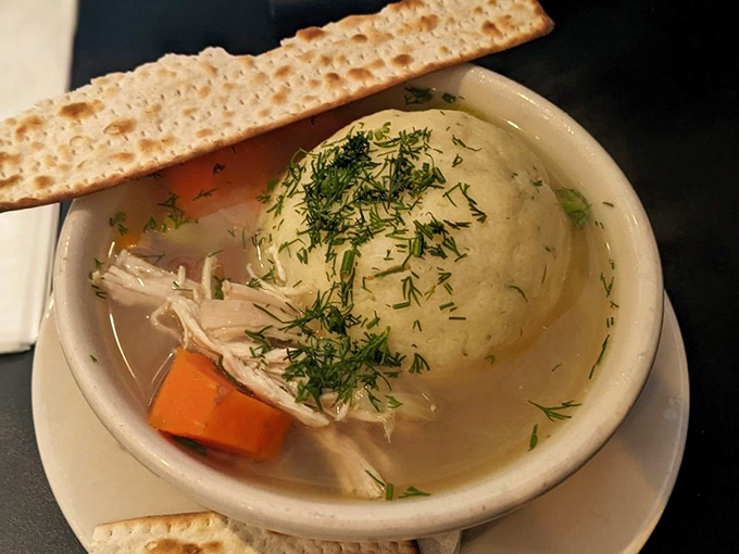 The matzo ball floats in golden broth like the moon in a chicken-flavored sky &ndash; penicillin without the prescription.