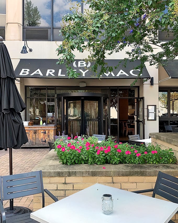 The outdoor seating area, framed by vibrant flowers, offers a peaceful urban oasis where summer evenings stretch deliciously long.