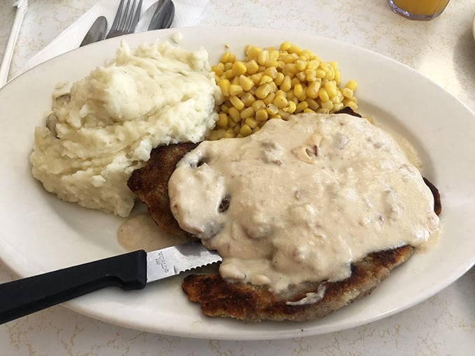 Country fried steak swimming in gravy alongside mashed potatoes that could make a grown adult cry. This isn't just comfort food&mdash;it's emotional support on a plate.