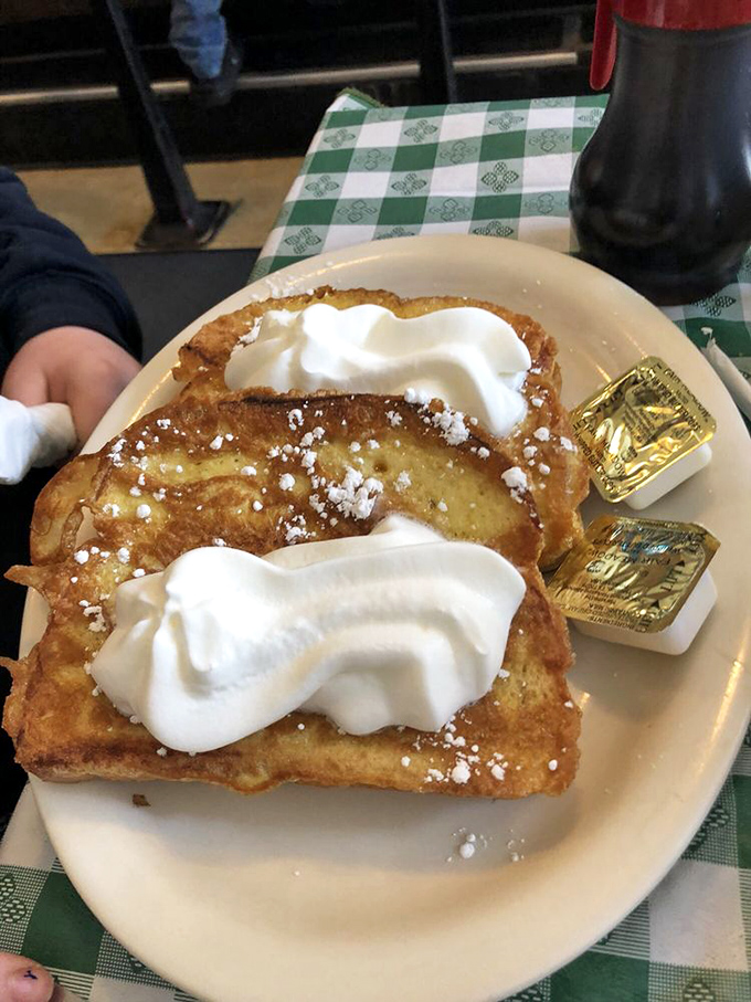 French toast so fluffy, it could double as a pillow. Topped with a cloud of whipped cream, it's the breakfast of sweet-toothed champions.