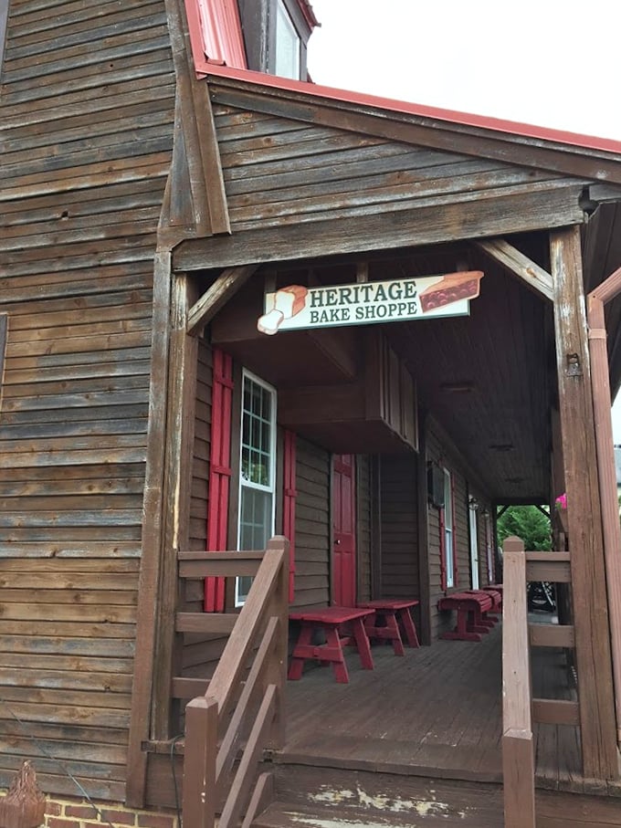 The welcoming wooden porch of Heritage Bake Shoppe, complete with rustic red benches, invites you to sit a spell before diving into their legendary pies. This isn't just an entrance&mdash;it's a time machine to simpler days.