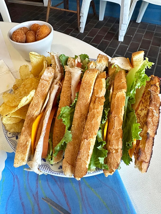A club sandwich stacked higher than most architectural achievements, with hush puppies standing guard. This isn't lunch&mdash;it's an event.