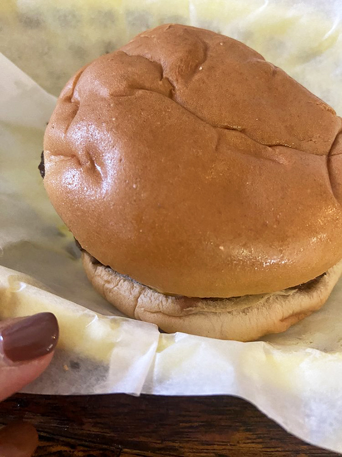 The humble hero of handheld heaven. This perfectly steamed bun cradles its precious cargo like a mother holding her newborn burger baby.