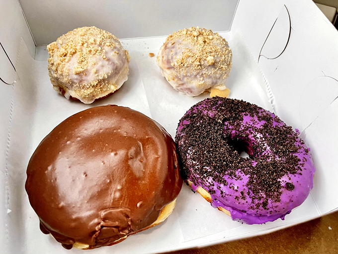 Donut royalty in one box. That purple-glazed beauty with chocolate crumbles isn't just a donut—it's Jacksonville's answer to formal dessert.