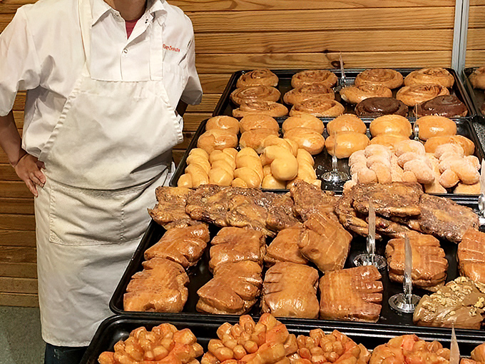 Fresh batches of golden perfection await their destiny. That tray of apple fritters is basically the donut equivalent of front-row concert tickets.