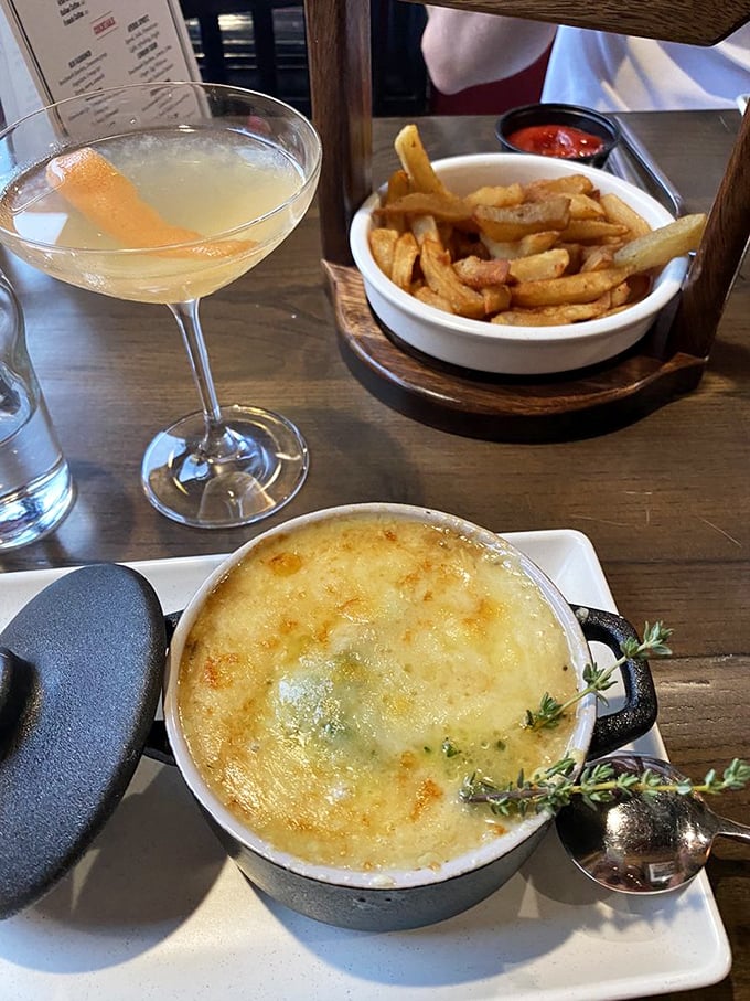The holy trinity of comfort: a steaming bowl of French onion soup, crispy fries, and a cocktail that sparkles like Alabama sunshine. Talk about a triple threat!