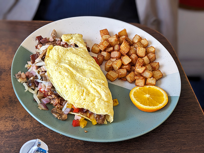 A perfect omelet isn't just breakfast, it's architecture&mdash;fluffy egg exterior protecting a treasure trove of fillings, with home fries standing guard.