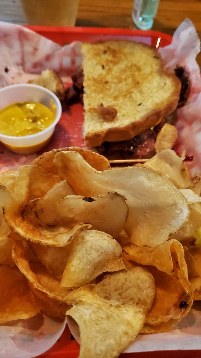 Pastrami perfection on a plate! This sandwich is stacked higher than a Jenga tower, with crispy chips standing guard like delicious sentinels.