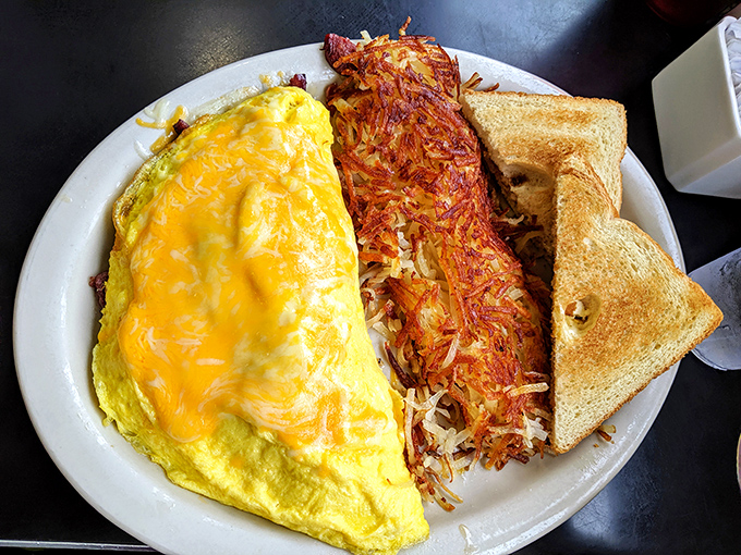 The holy trinity of breakfast: a golden omelet, crispy hash browns, and toast so perfect it could make a carb-counter weep with joy.