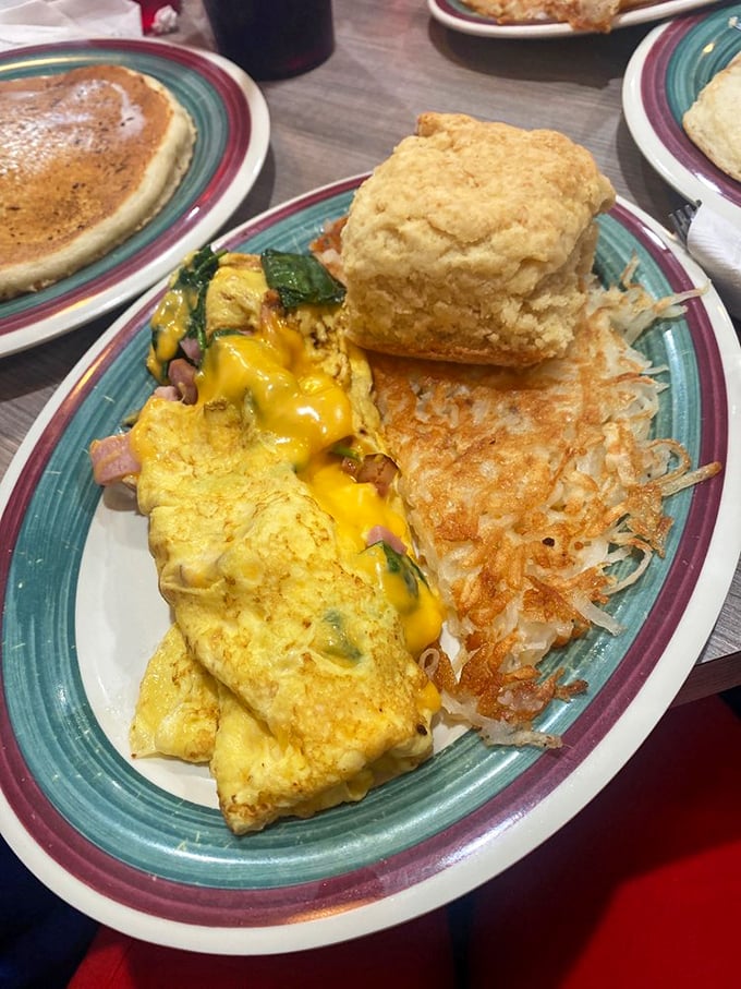 Behold, the holy trinity of breakfast: a golden omelet, crispy hash browns, and a biscuit that could make a Southerner weep with joy.