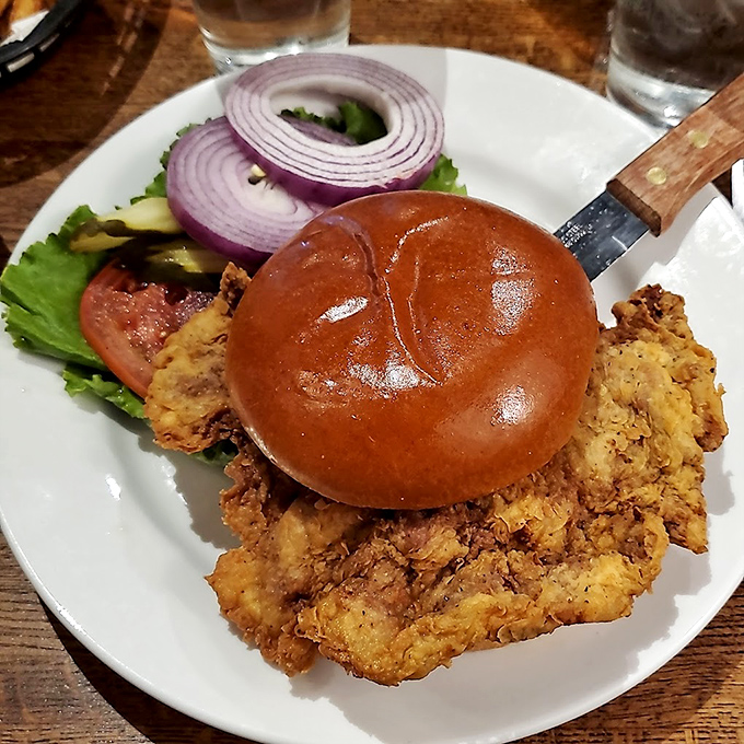 The famous pork tenderloin sandwich arrives like an edible gold medal&mdash;crispy, golden breading dramatically overhanging a bun that's struggling to keep up.