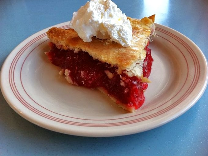 Ruby red perfection! This strawberry rhubarb pie is summer on a plate, crowned with a cloud of whipped cream that's begging for its close-up.